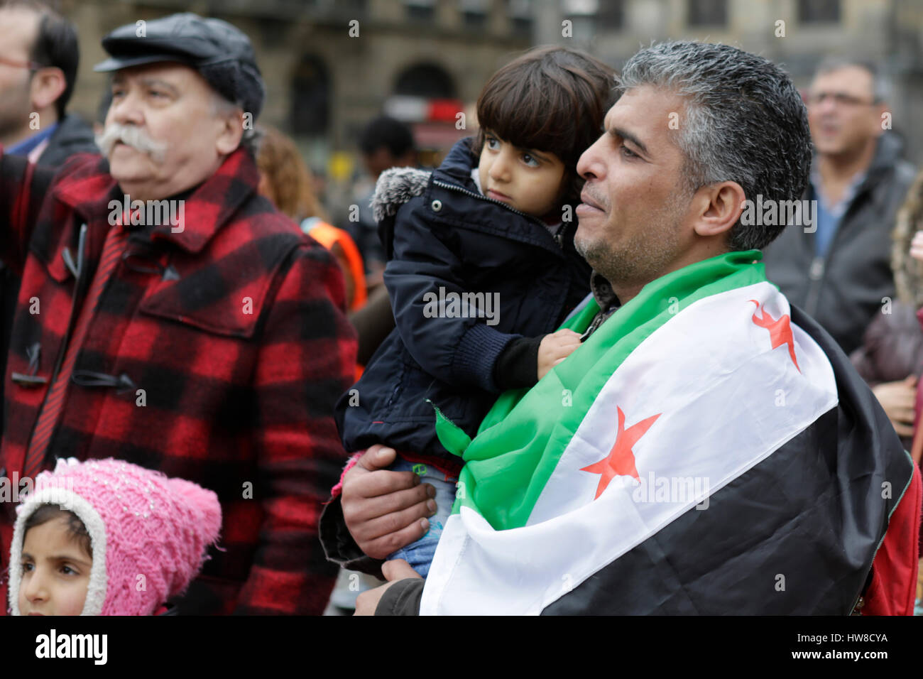 A Syrians father wears a Syria Independence flag over his shoulders and ...