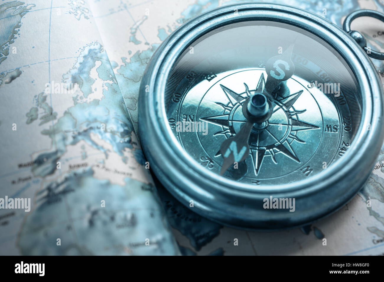 Compass on map background in blue toning Stock Photo - Alamy