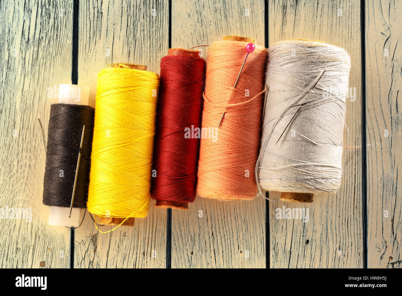 Thread bobbins and needles on paper background Stock Photo - Alamy
