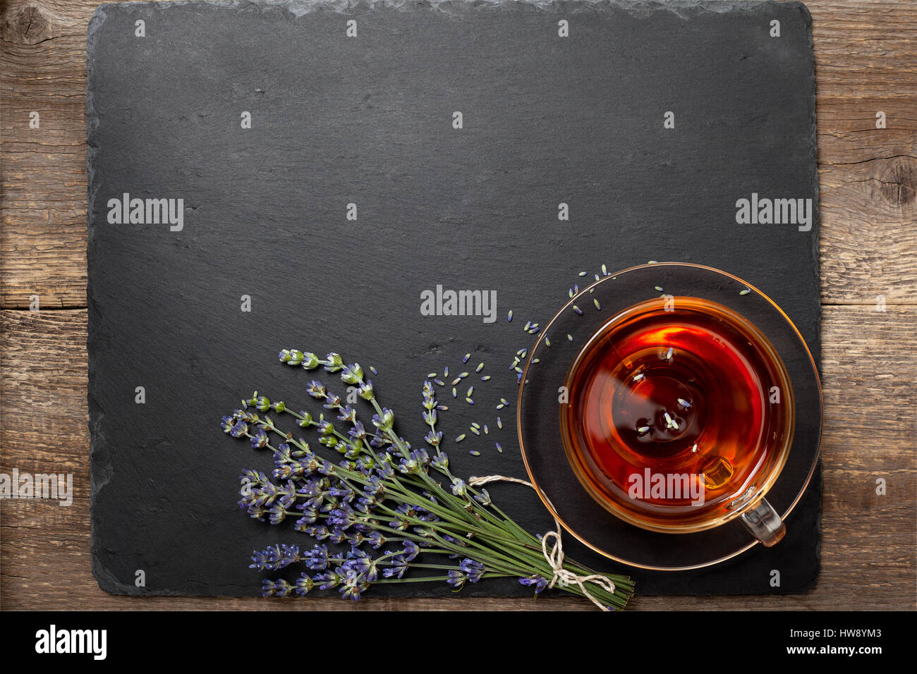 Lavender tea in a glass cup, bouquet of fresh lavender on a black slate ...