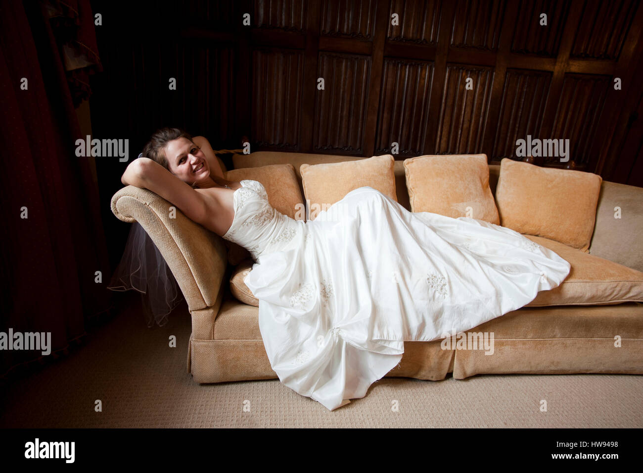 Young woman wearing a white wedding dress,lying on a sofa Stock Photo ...