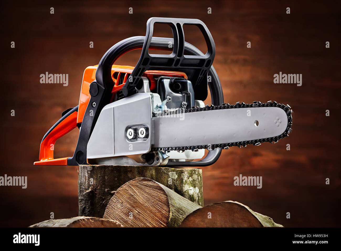 Cut logs fire wood and chainsaw on brown wooden background. Renewable ...