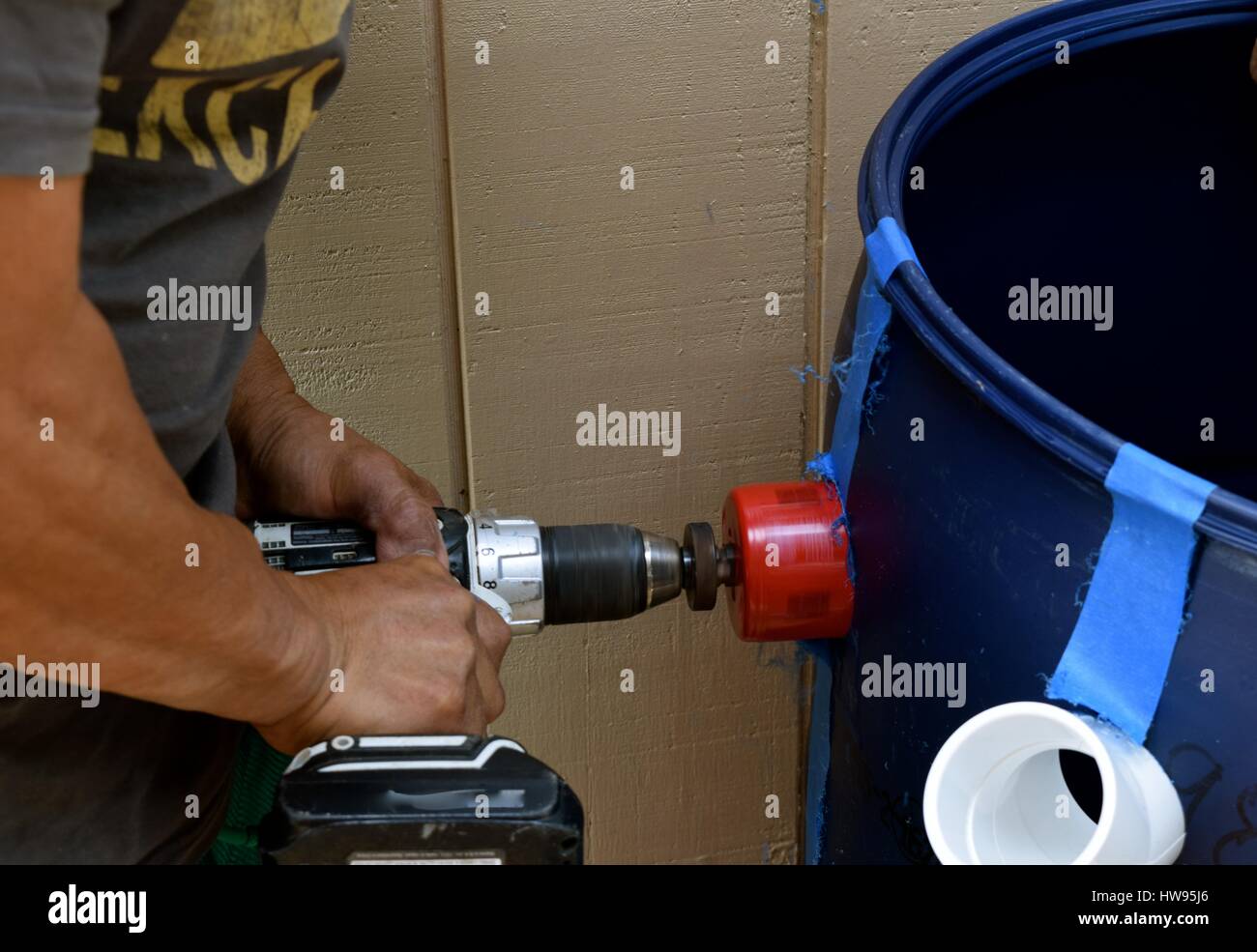 Man using a bit to drill holes into the container drum Stock Photo - Alamy