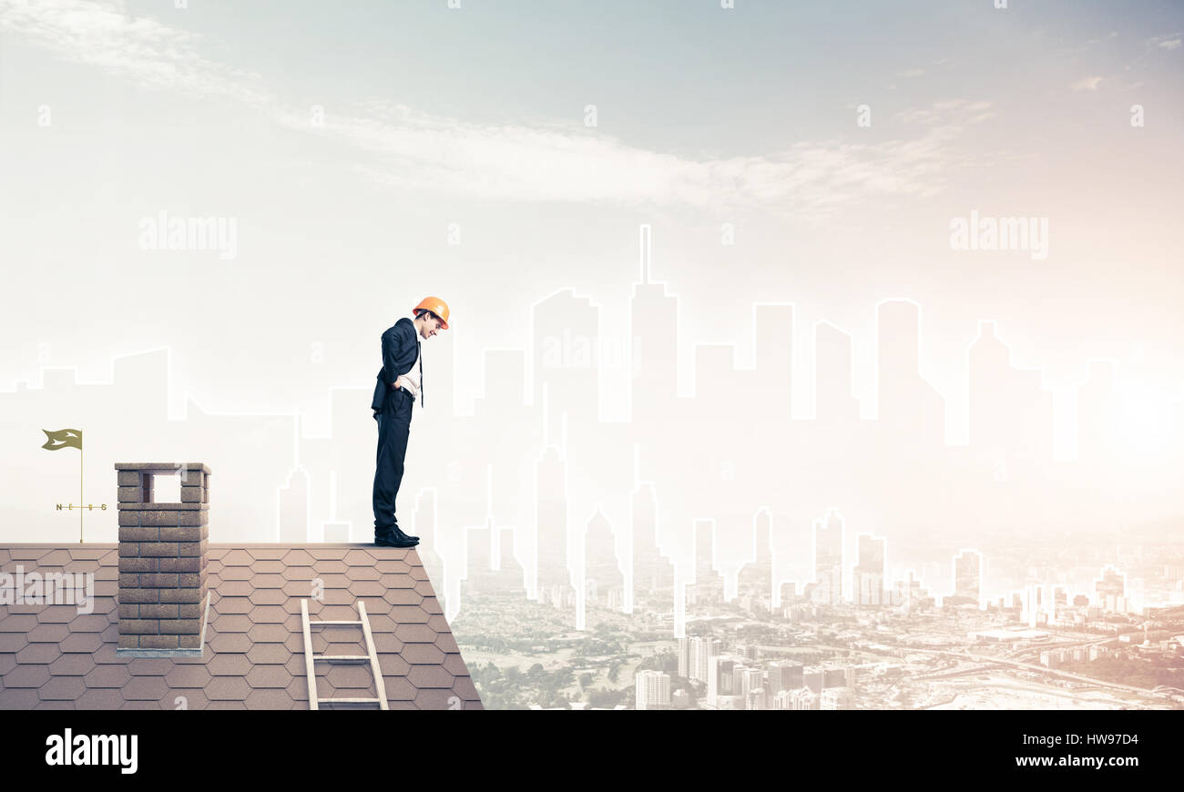 Engineer man standing on roof and looking down. Mixed media Stock Photo ...