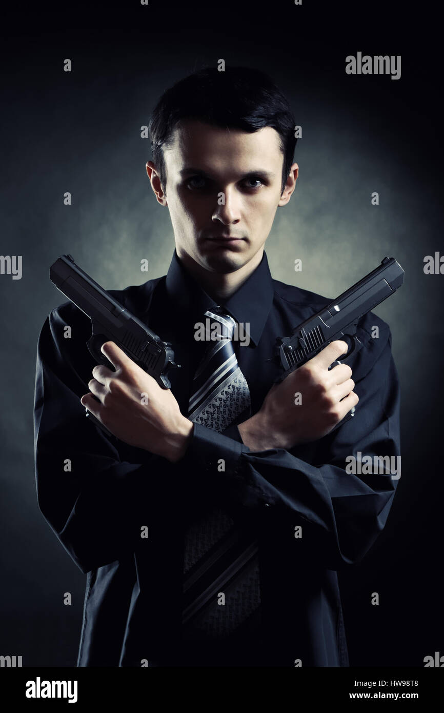Killer with two pistols on dark background Stock Photo - Alamy
