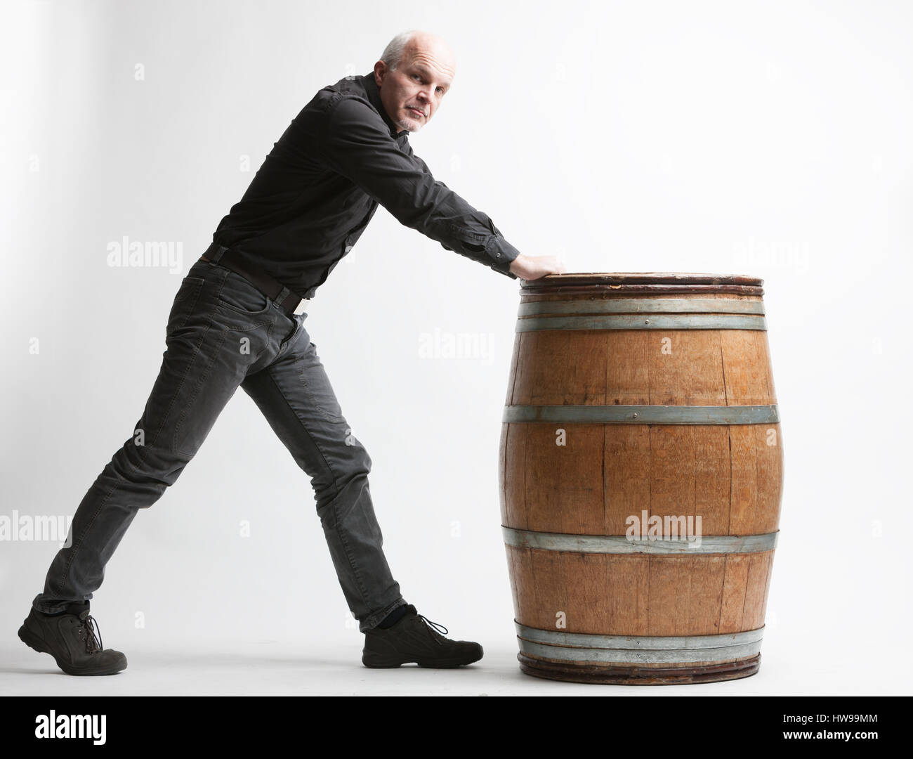 Man in dark casual clothes holding old wooden barrel by the edge ...