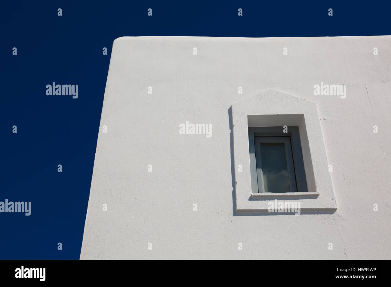 Window detail in a rectangular wall on a white Greek villa against a ...