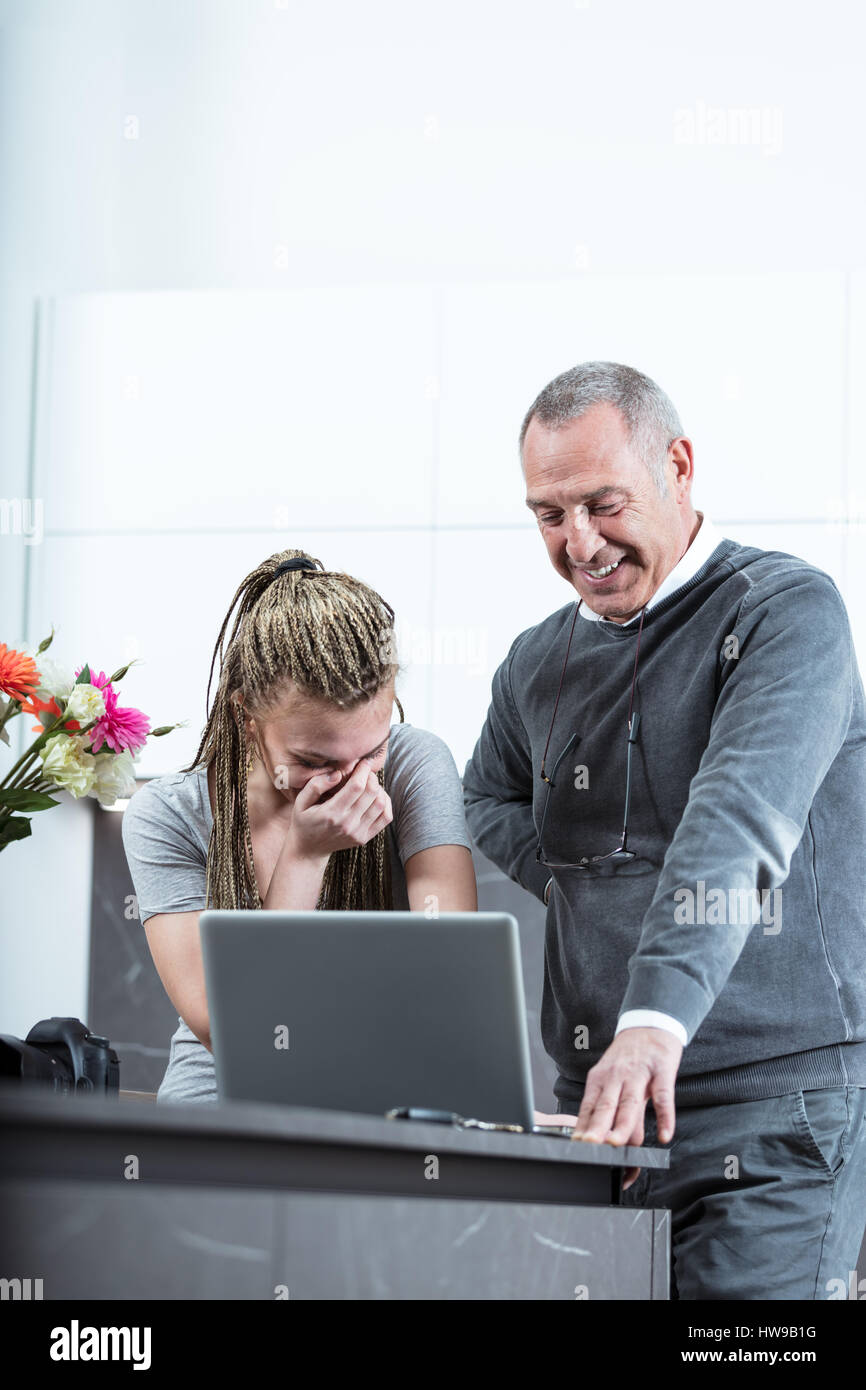 Young woman and elderly man laughing looking at computer screen Stock ...