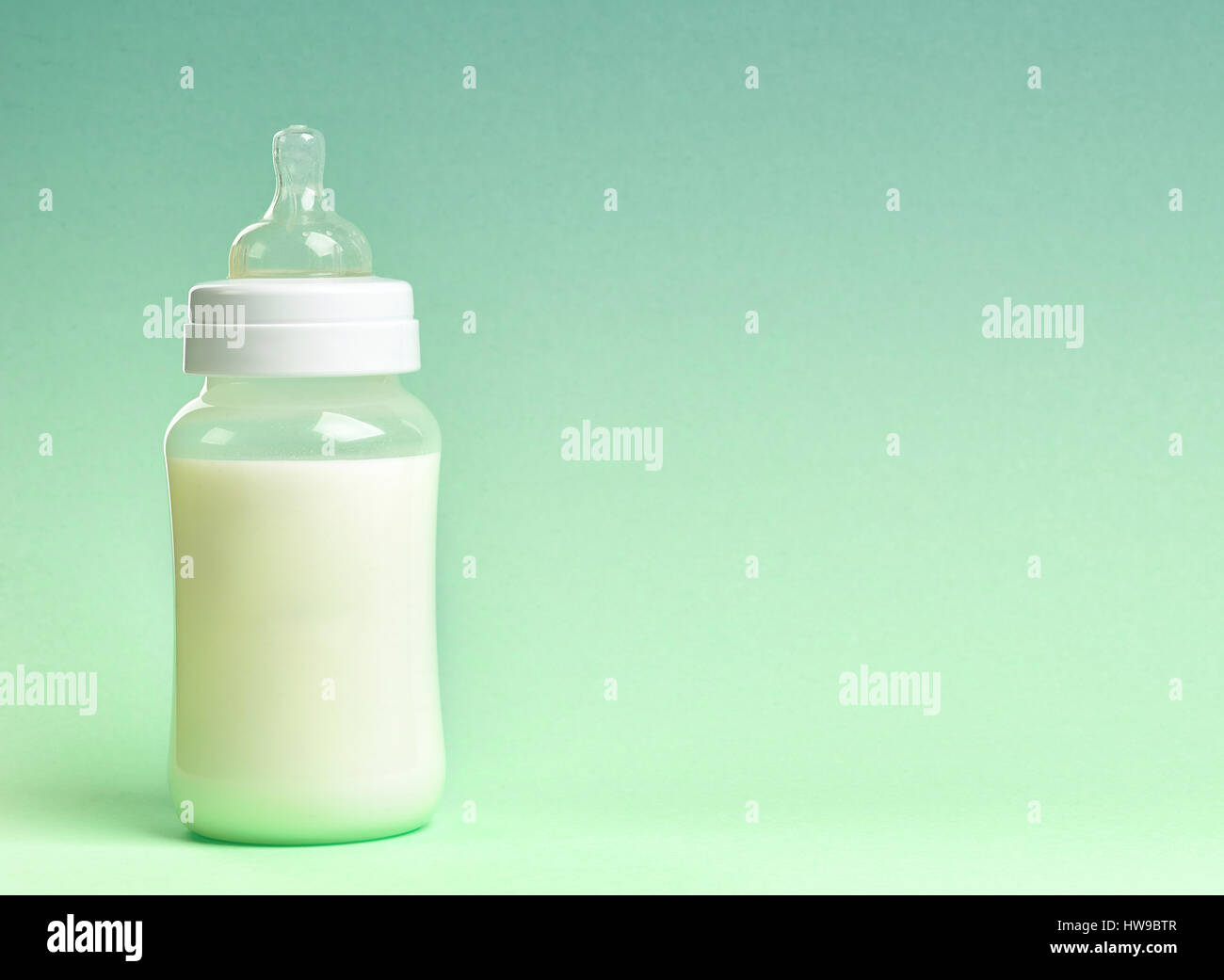 baby milk bottle on green background Stock Photo - Alamy