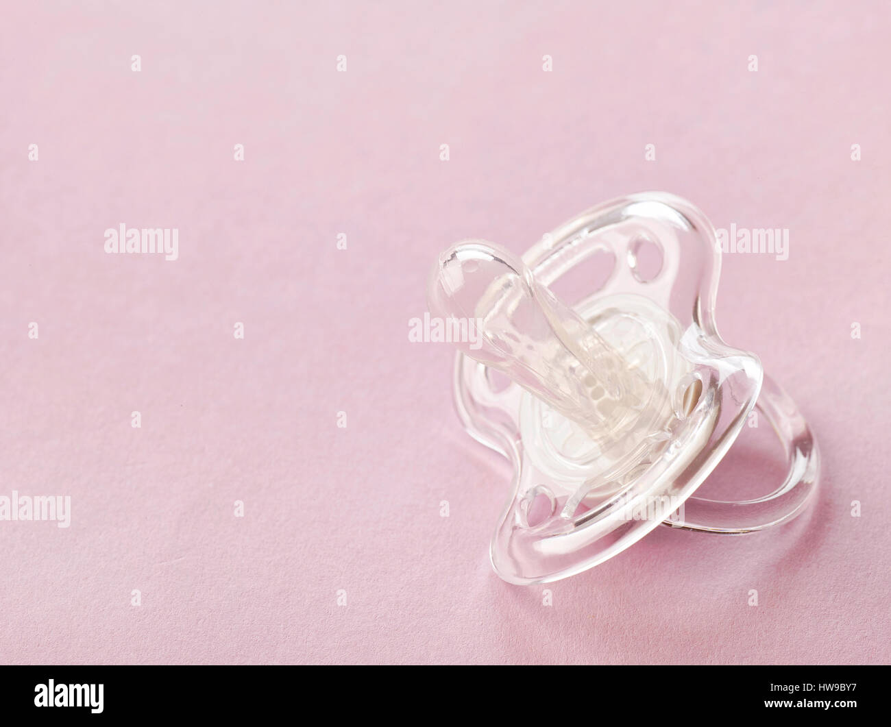 transparent pacifier on pink paper background Stock Photo - Alamy
