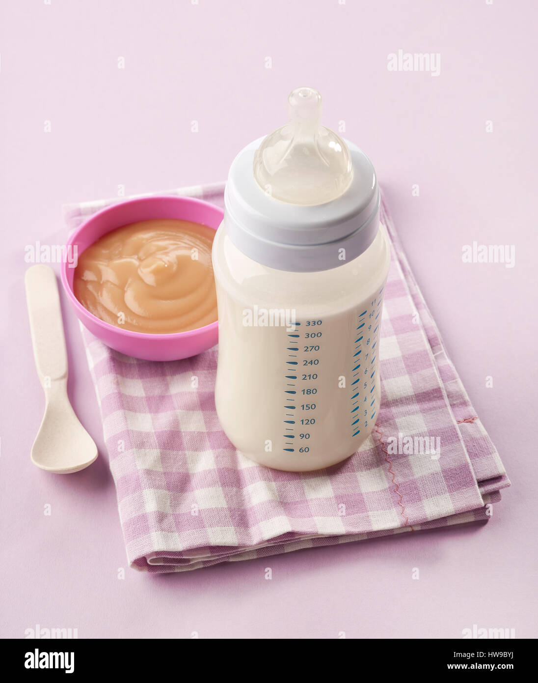 baby milk bottle and bowl of pureed apple on purple background Stock ...