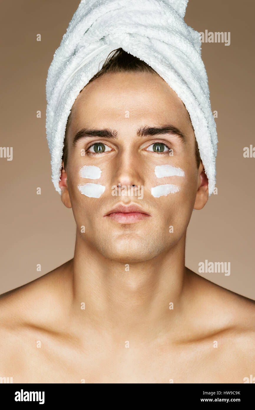 Young man with moisturizer on the face. Photo of handsome man with ...