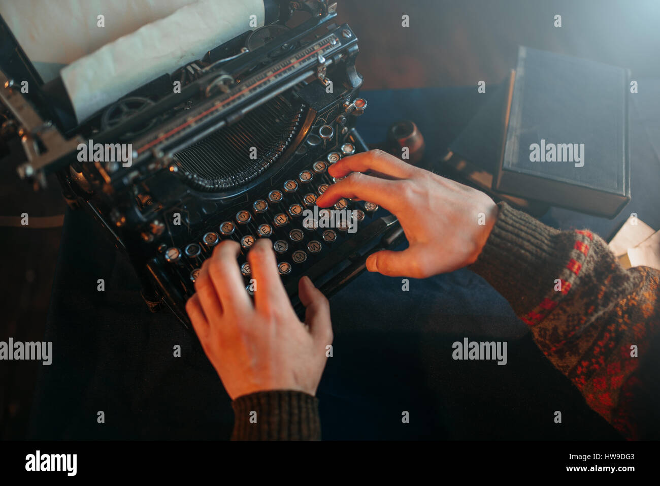 Male hands typing on retro typewriter, top view. Dark blue table cloth on background. Writer ...