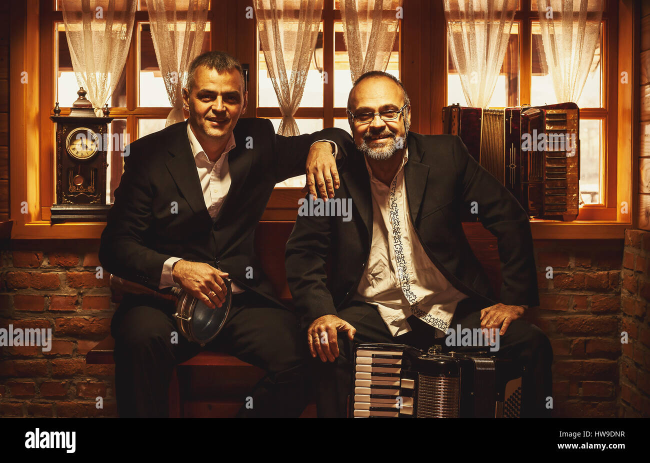 Portraits of percussionist and accordionist in front of a wooden window ...