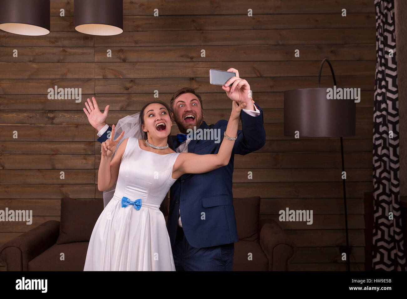 Smiling bride and groom making selfie on mobile phone, wooden ...