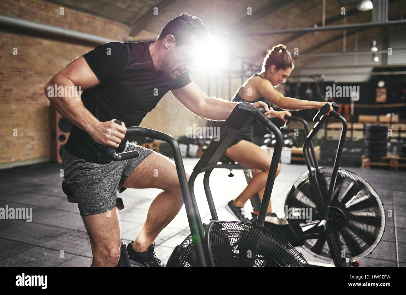 Young man in backlit and woman riding in hard efforts on cycling ...