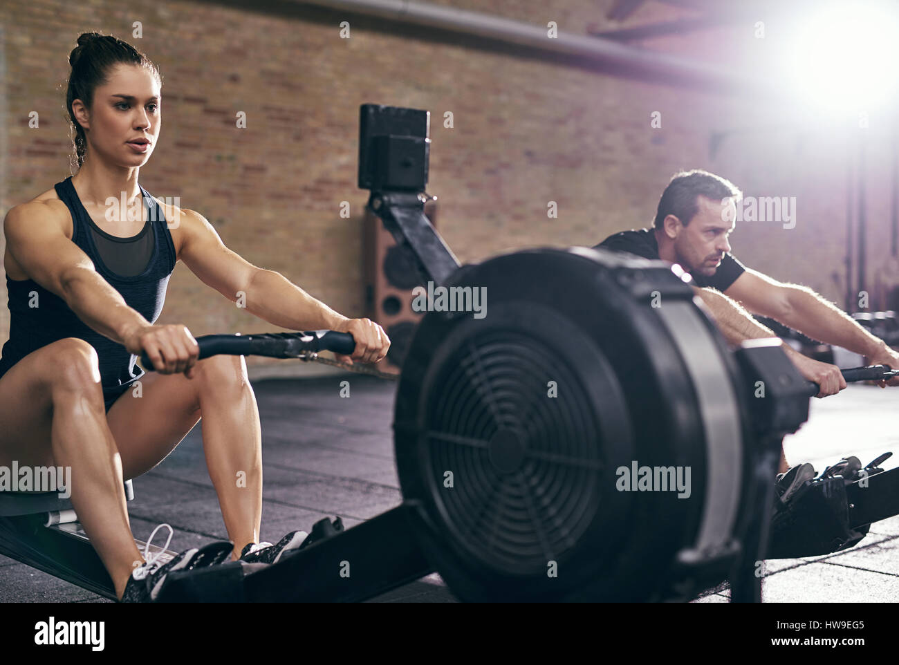 Young sportive man and woman in sportswear exercising on body-builders ...