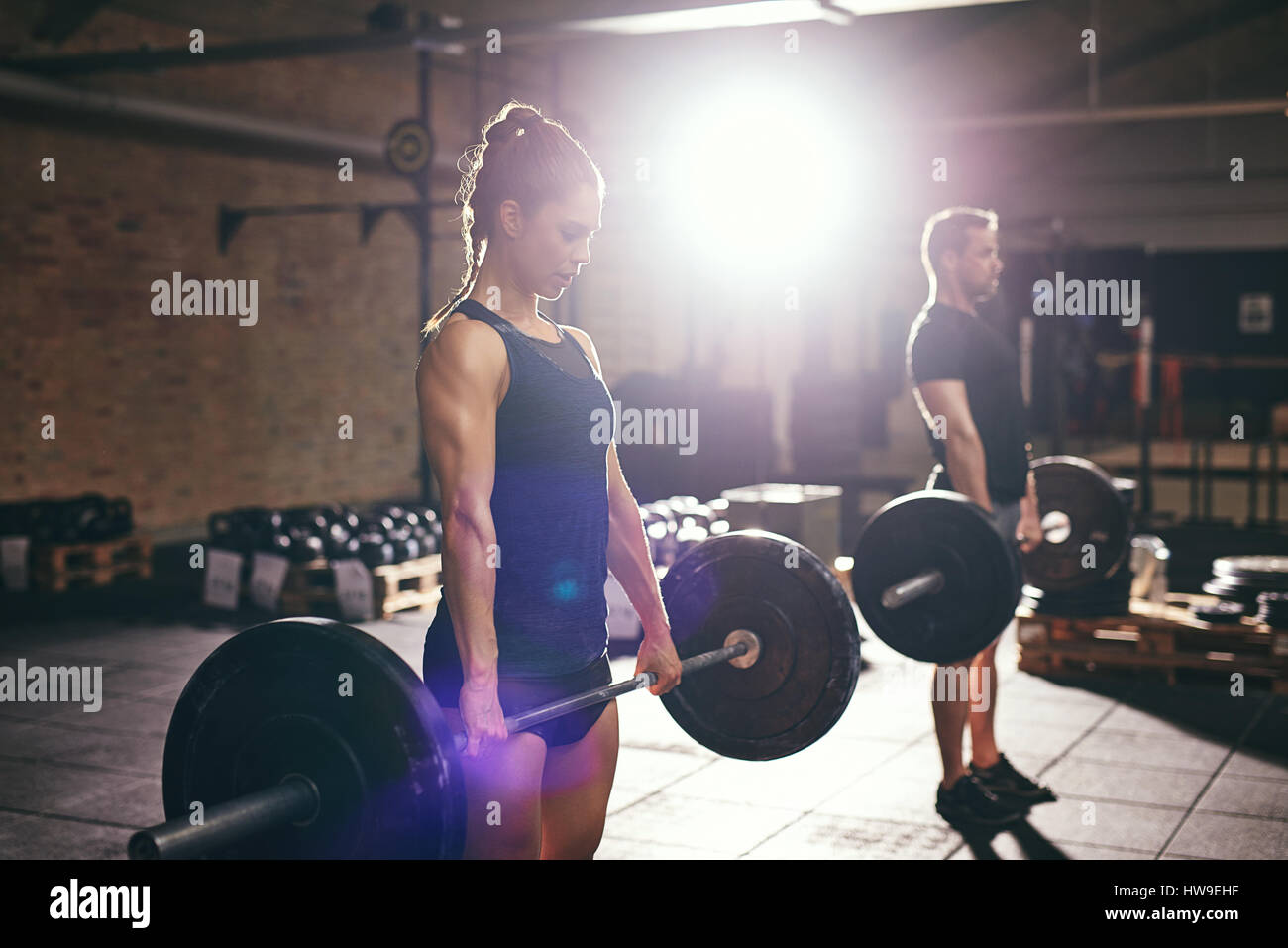 Two young muscular people at gym lifting barbells with arms Stock Photo ...