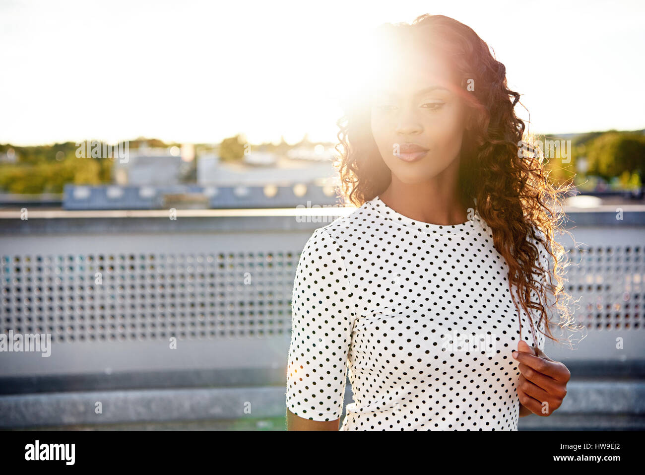 Sunlit portrait of a pretty black woman with curly hair posing for ...