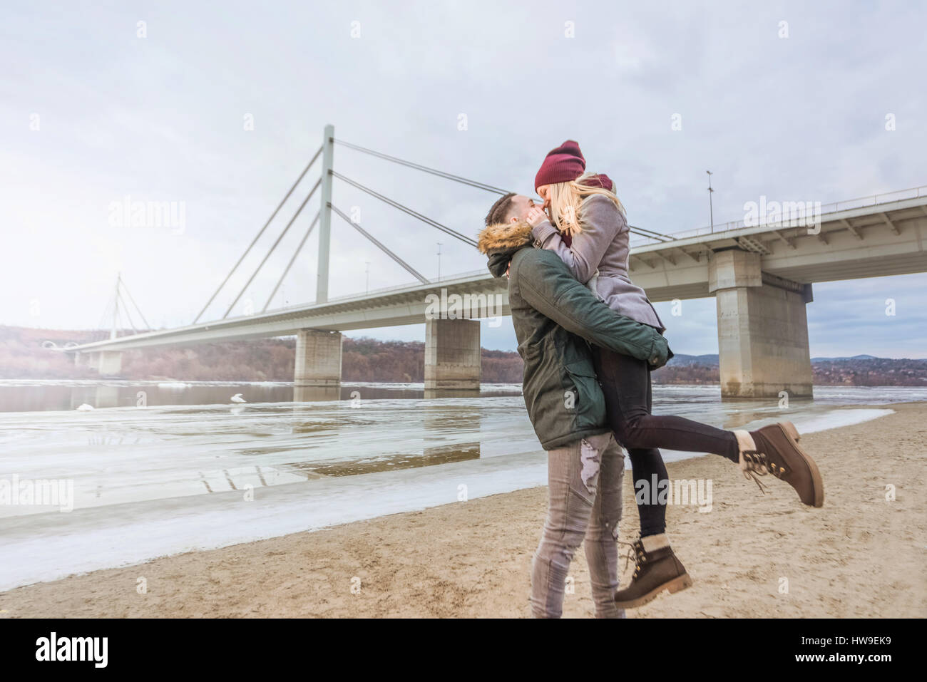 Beautiful young couple hugging next to bridge Stock Photo - Alamy