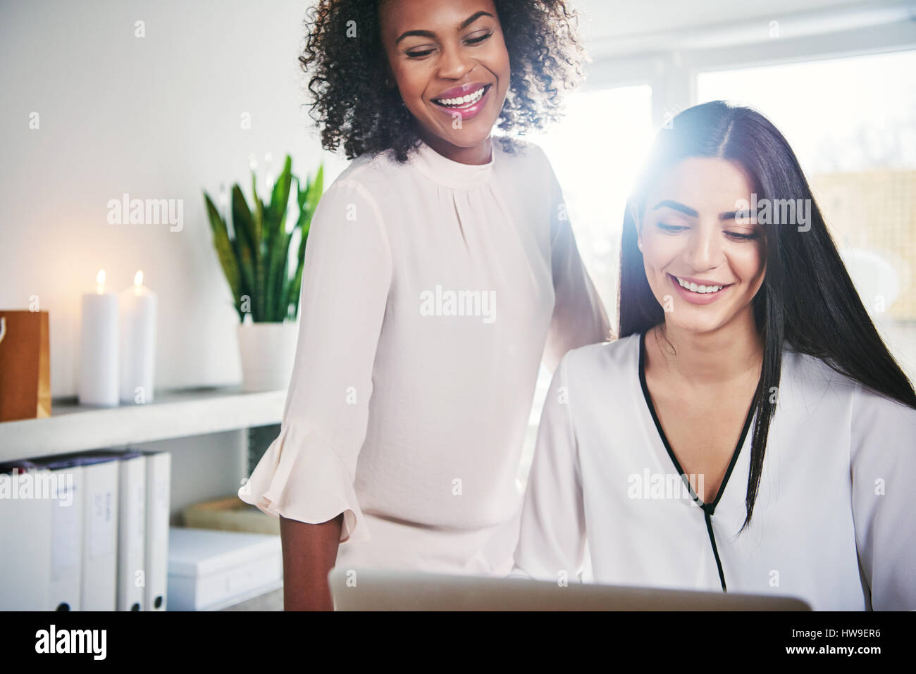 Happy successful young women entrepreneurs working together at a laptop ...
