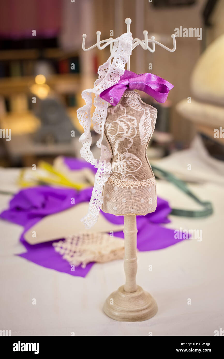 Small decorative female mannequin on table in sewing studio. Jewelry ...