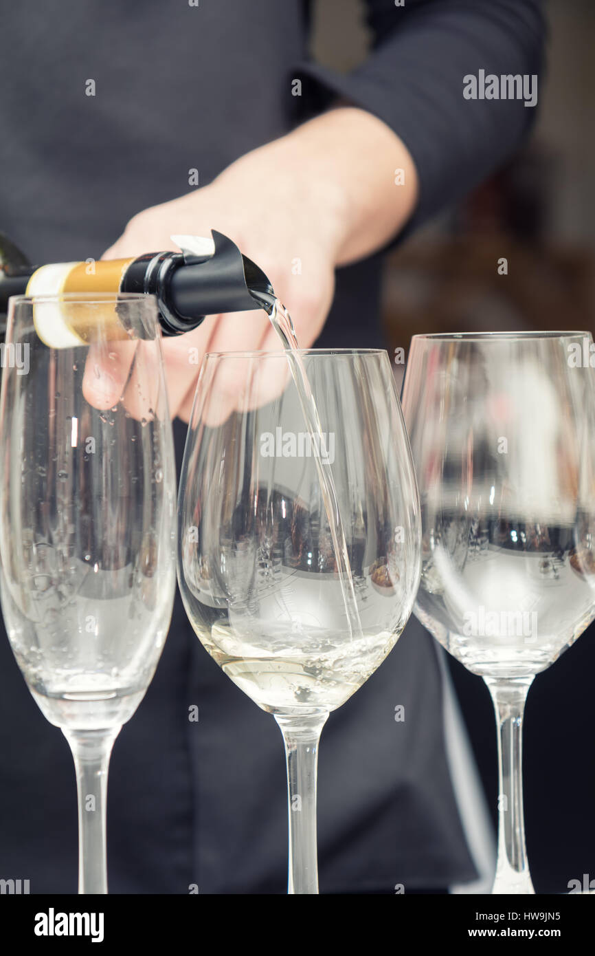 Sommelier pouring white wine to the wine glass. Serving table prepared ...