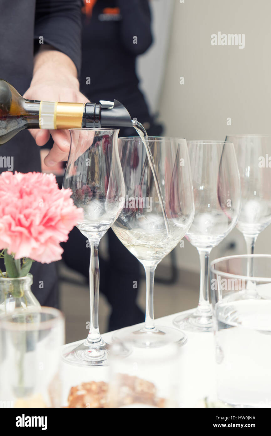 Sommelier pouring white wine to the wine glass. Serving table prepared ...