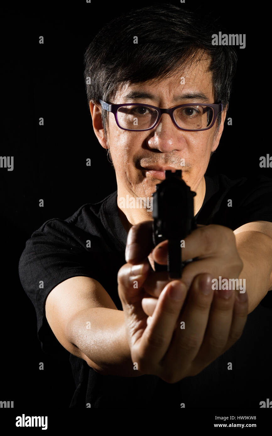 Asian Chinese Man Holding a Gun in isolated Black Background Stock ...