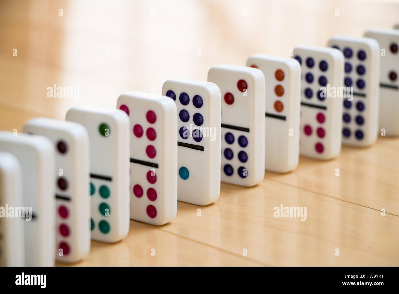 Straight Line of Colorful Dominoes on Wooden Floor Stock Photo - Alamy