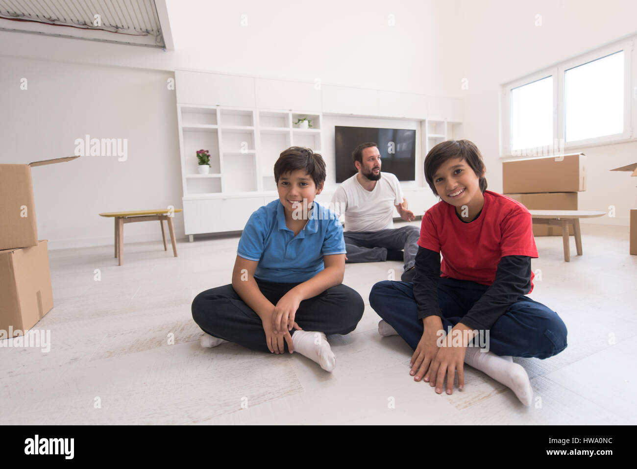 portrait of happy young boys with their dad sitting on the floor in a ...