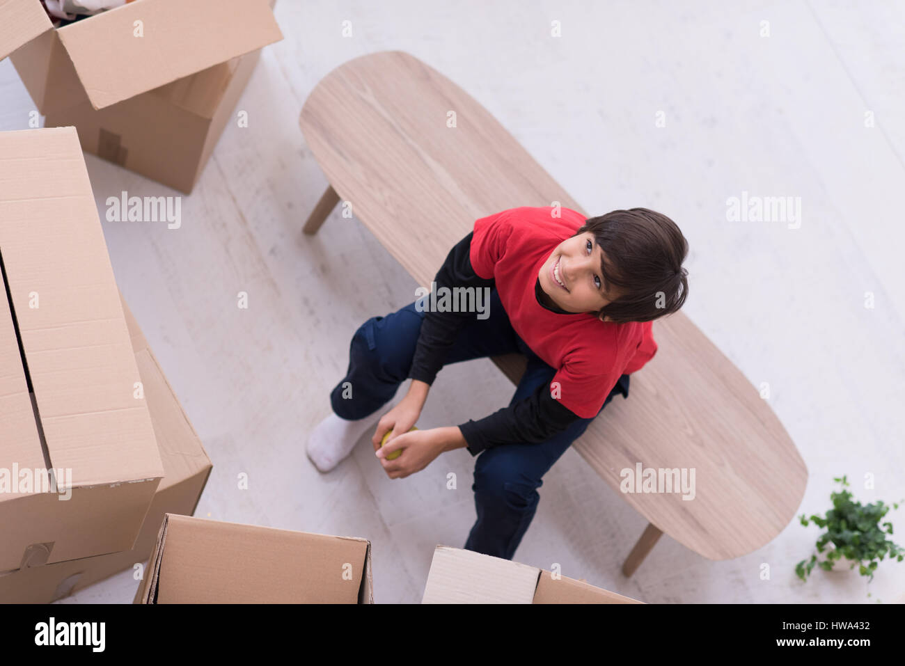 happy little boy sitting on the table with cardboard boxes around him ...