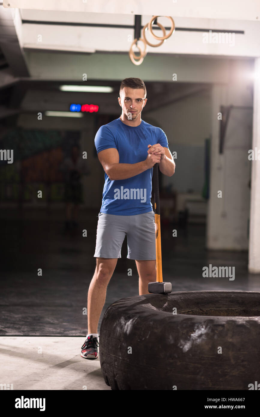 Sledgehammer Tire Hits young muscular man workout at gym with hammer ...