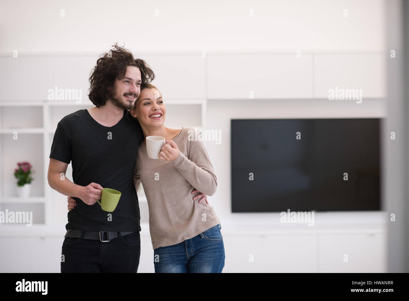 Portrait of a happy young beautiful couple hugging and drinking coffee ...