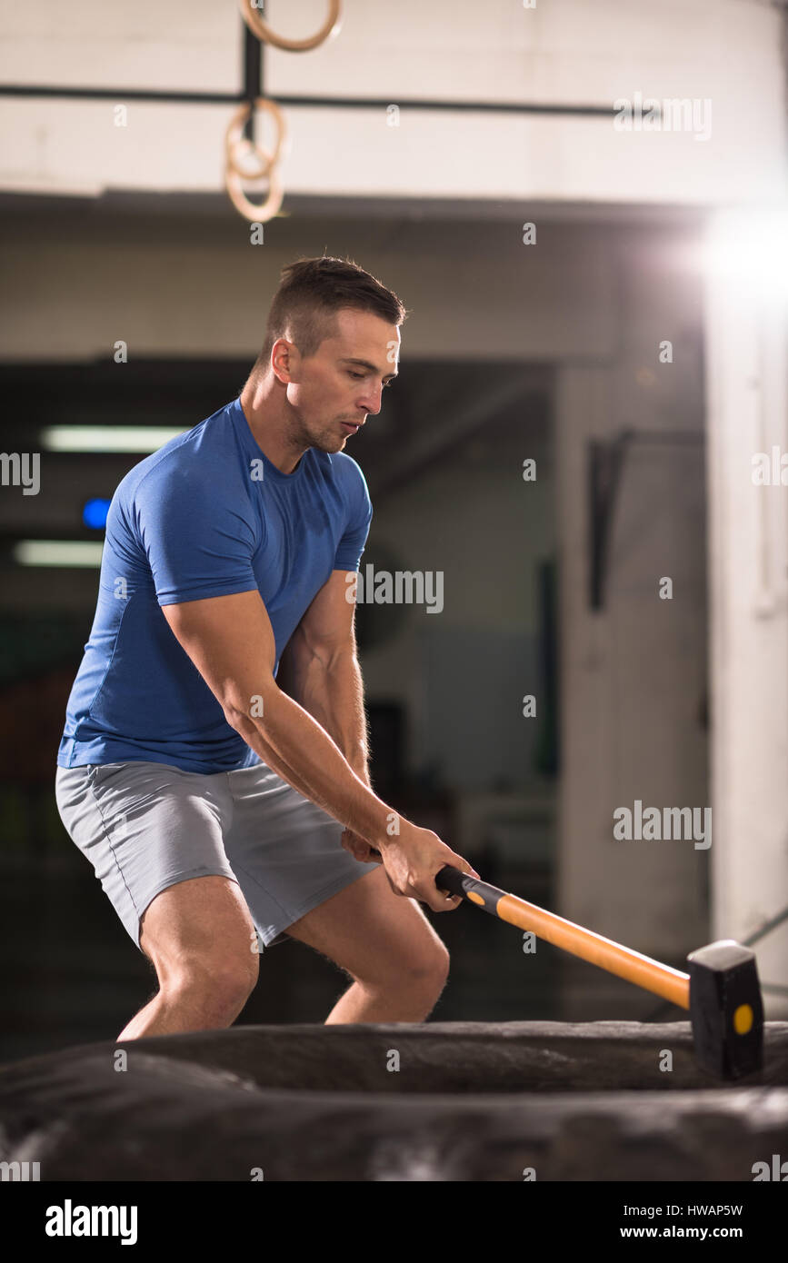 Sledgehammer Tire Hits young muscular man workout at gym with hammer ...