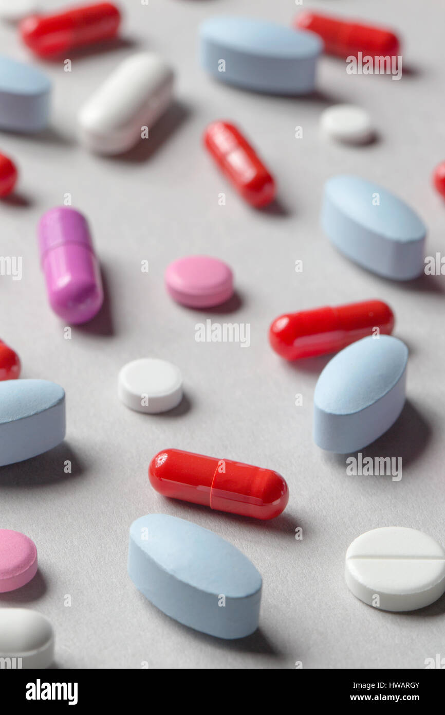 various colorful medicine pills on grey paper background, selective ...