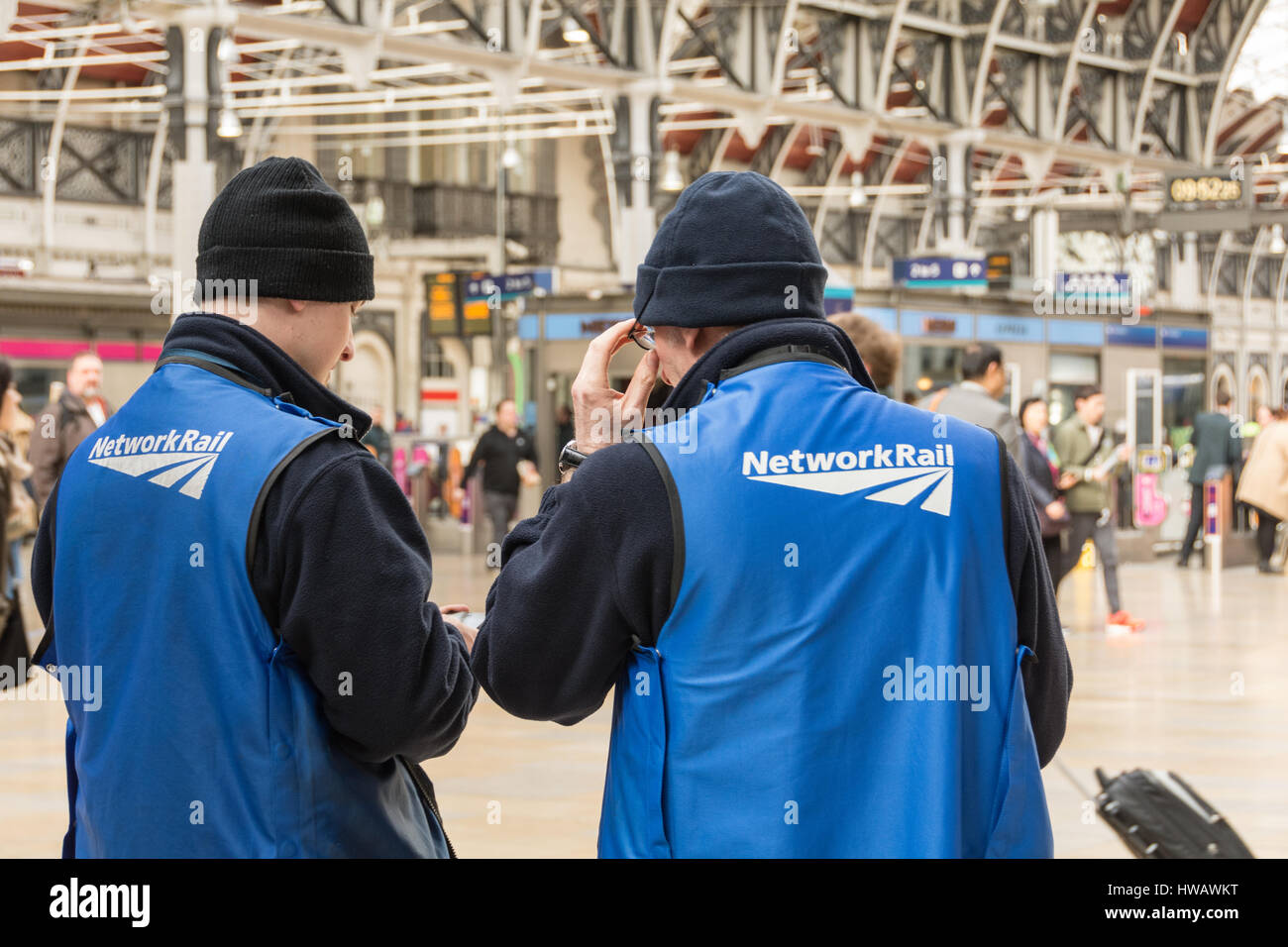 Closeup and rear view of two Network Rail station staff at Paddington ...