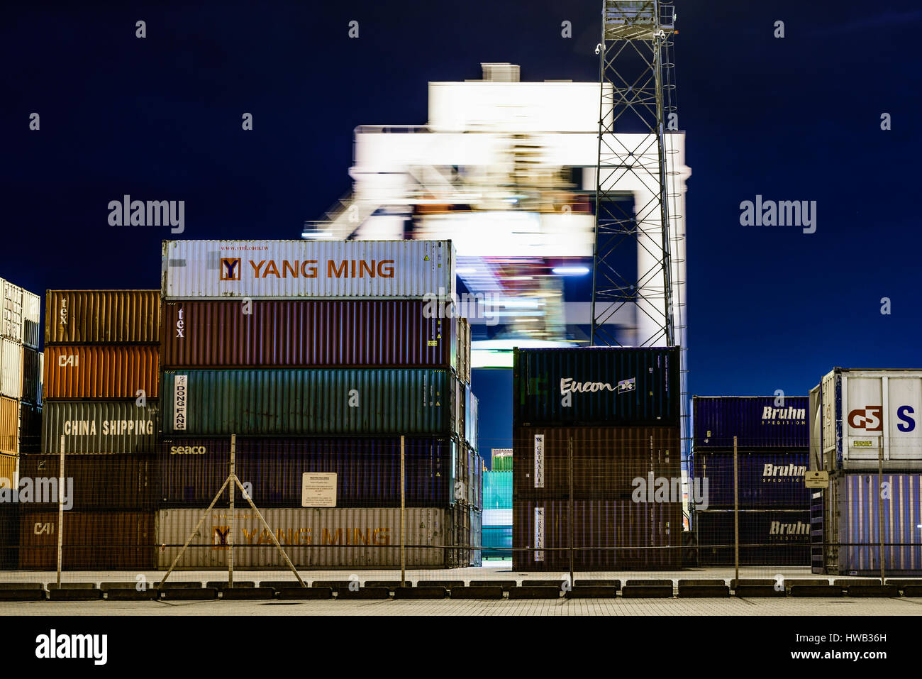 Shipping containers stacked up at a freight port, while a crane moves ...