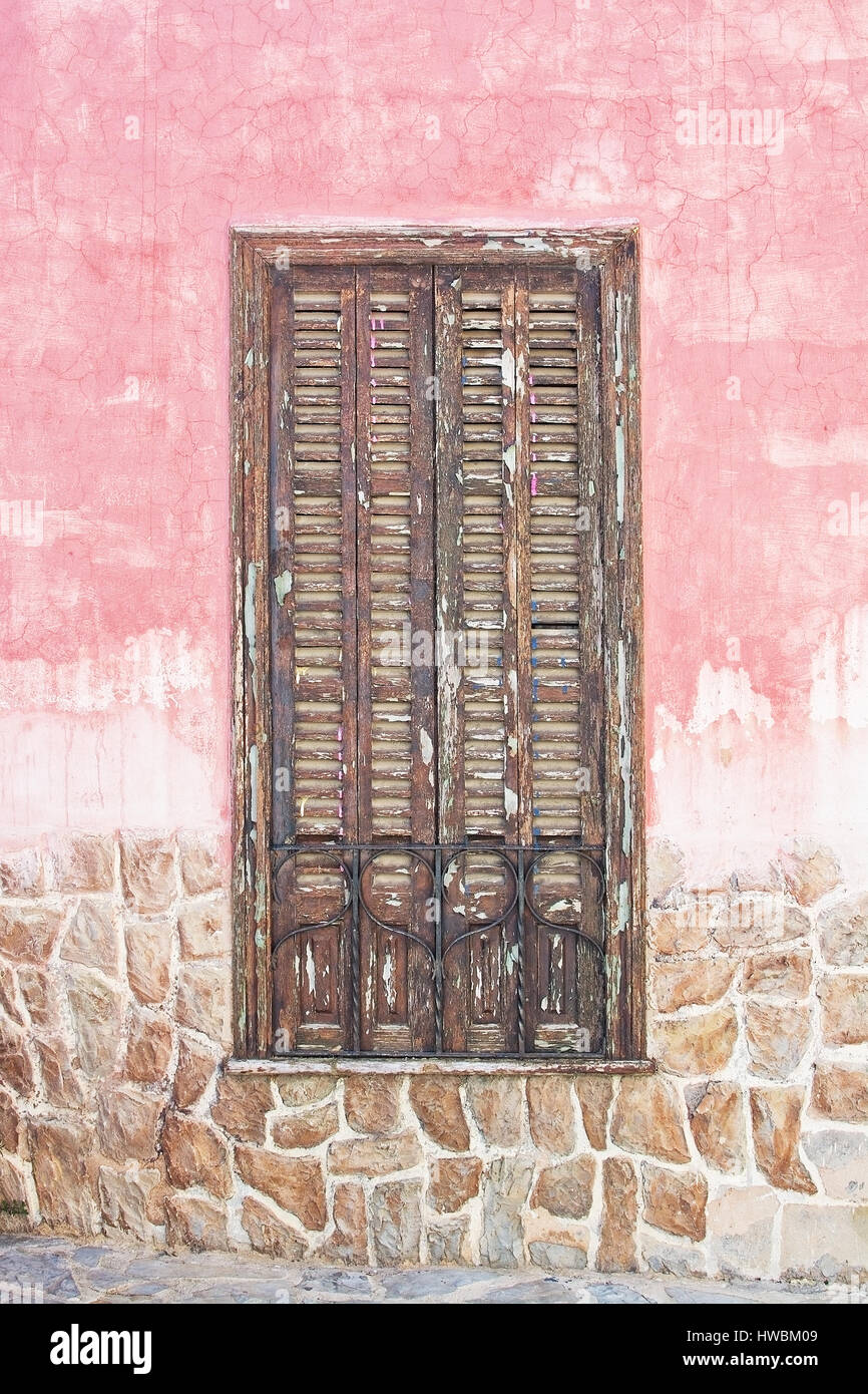 Brown wood window shutters on pink roughcast and stone wall in Mallorca ...