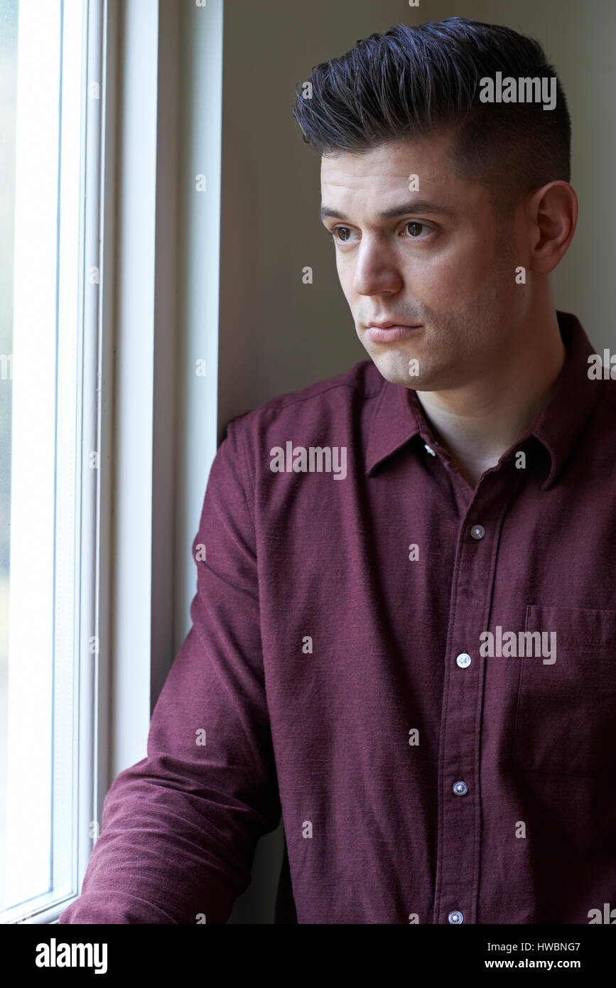 Sad Man Suffering From Depression Looking Out Of Window Stock Photo - Alamy