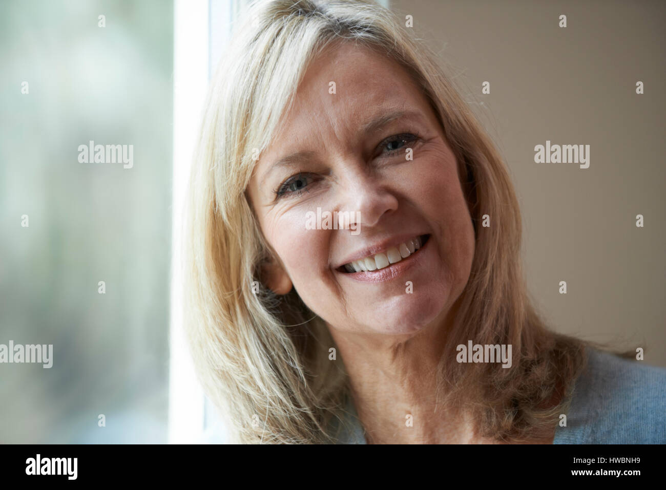 Smiling Mature Woman Standing Next To Window Stock Photo - Alamy