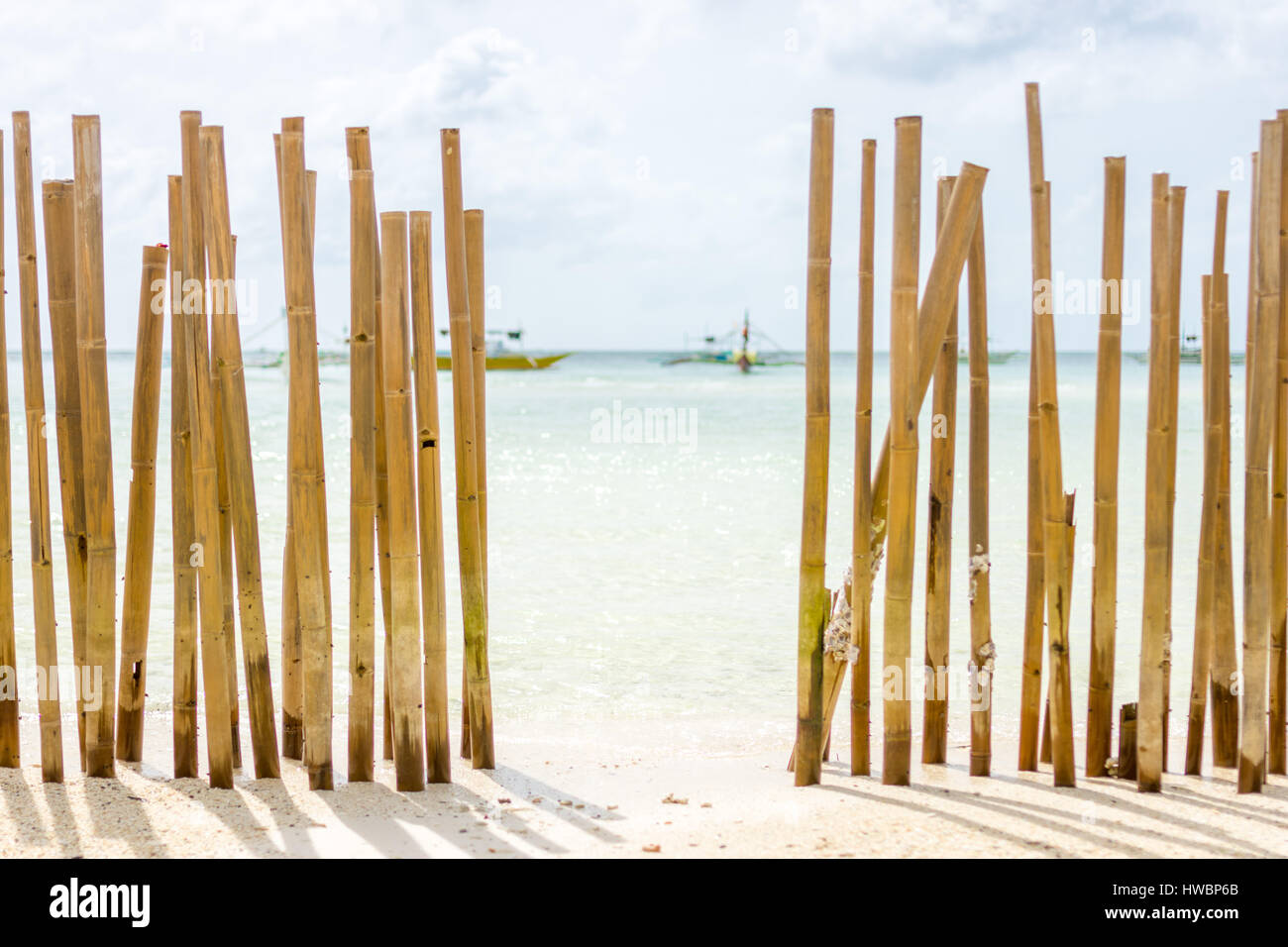 Looking through a bamboo pole barrier fence in a tropical island white ...