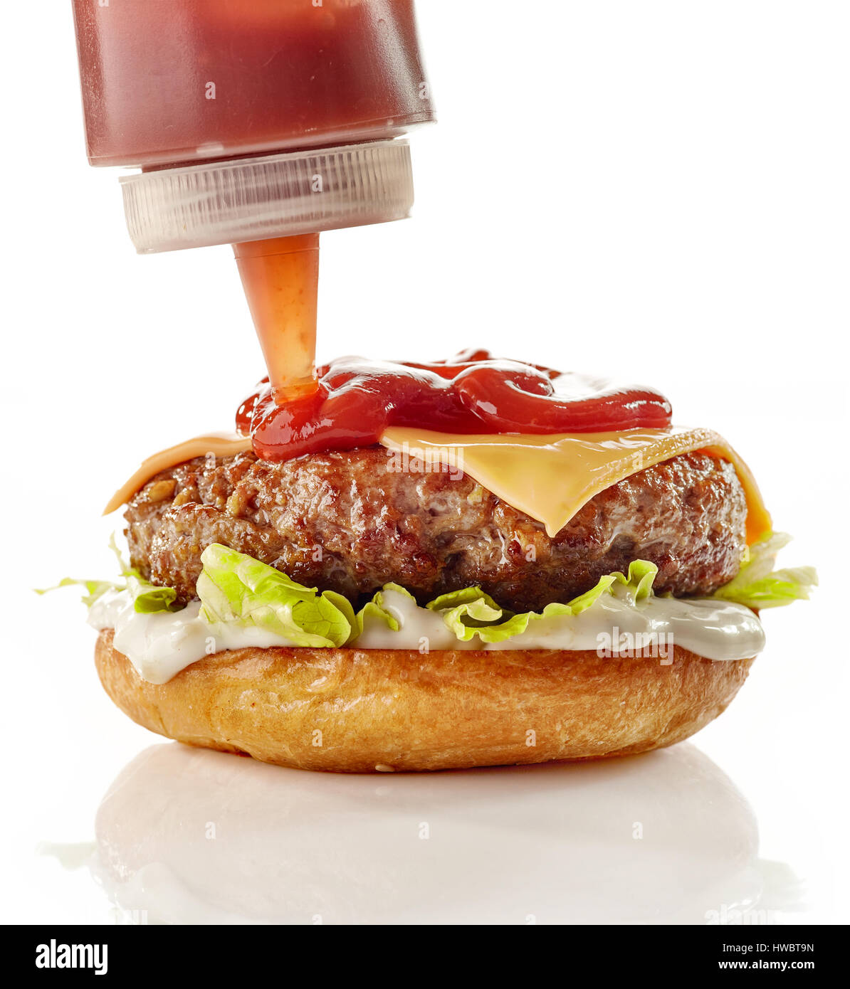 Cook adding tomato sauce on burger. Burger preparation isolated on ...