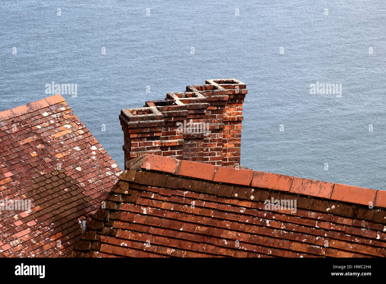 View looking down on well weathered red brick chimney stacks and tiles ...