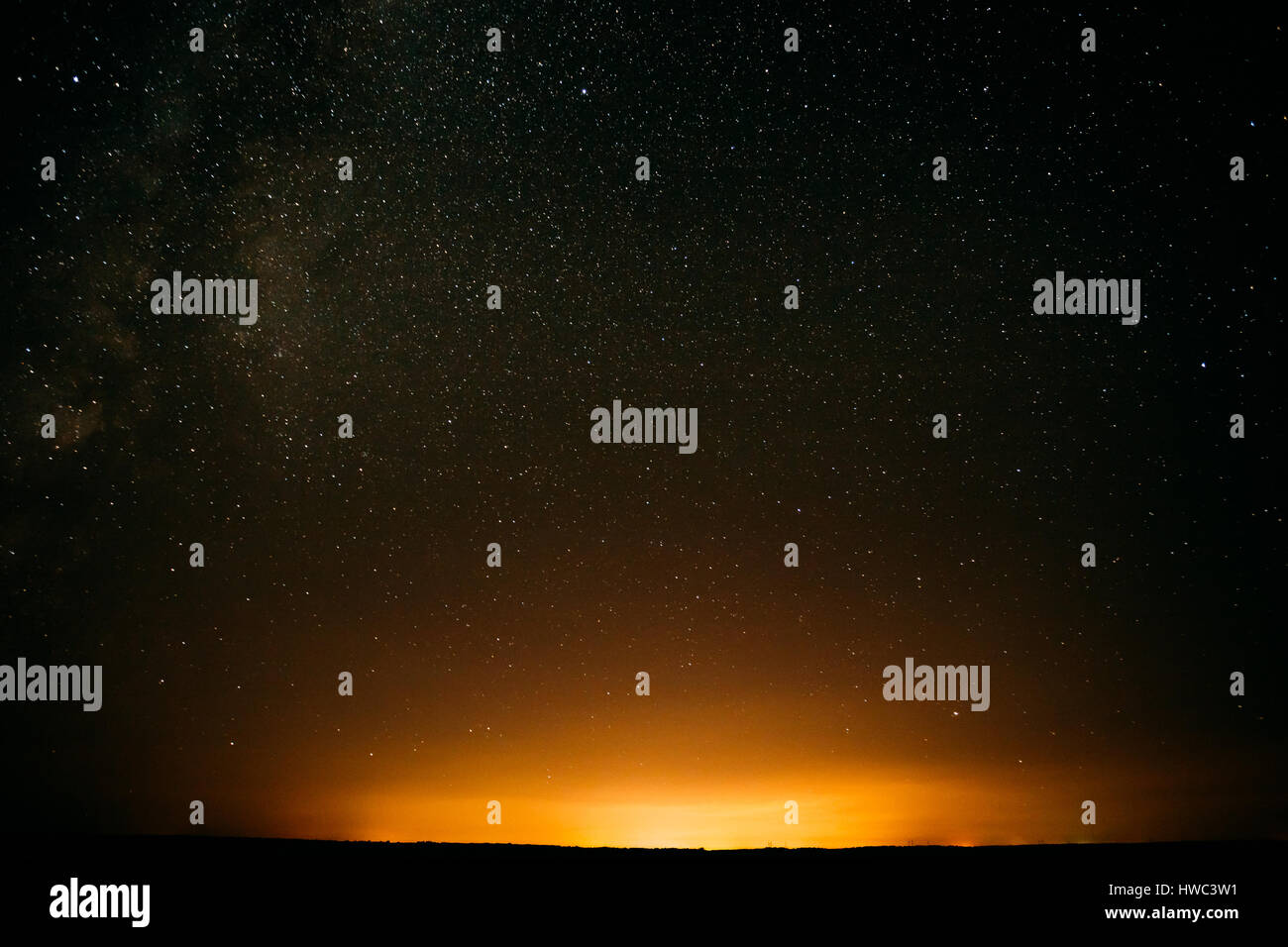 Night Starry Sky Above Field And Yellow City Lights On Background ...