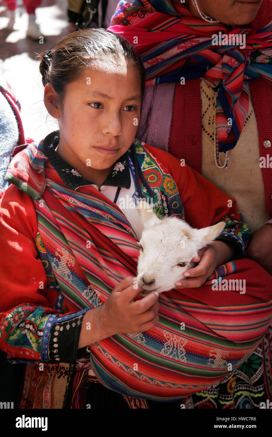 A child dressed in traditional garb holding a baby Alpaca in Cuzco ...