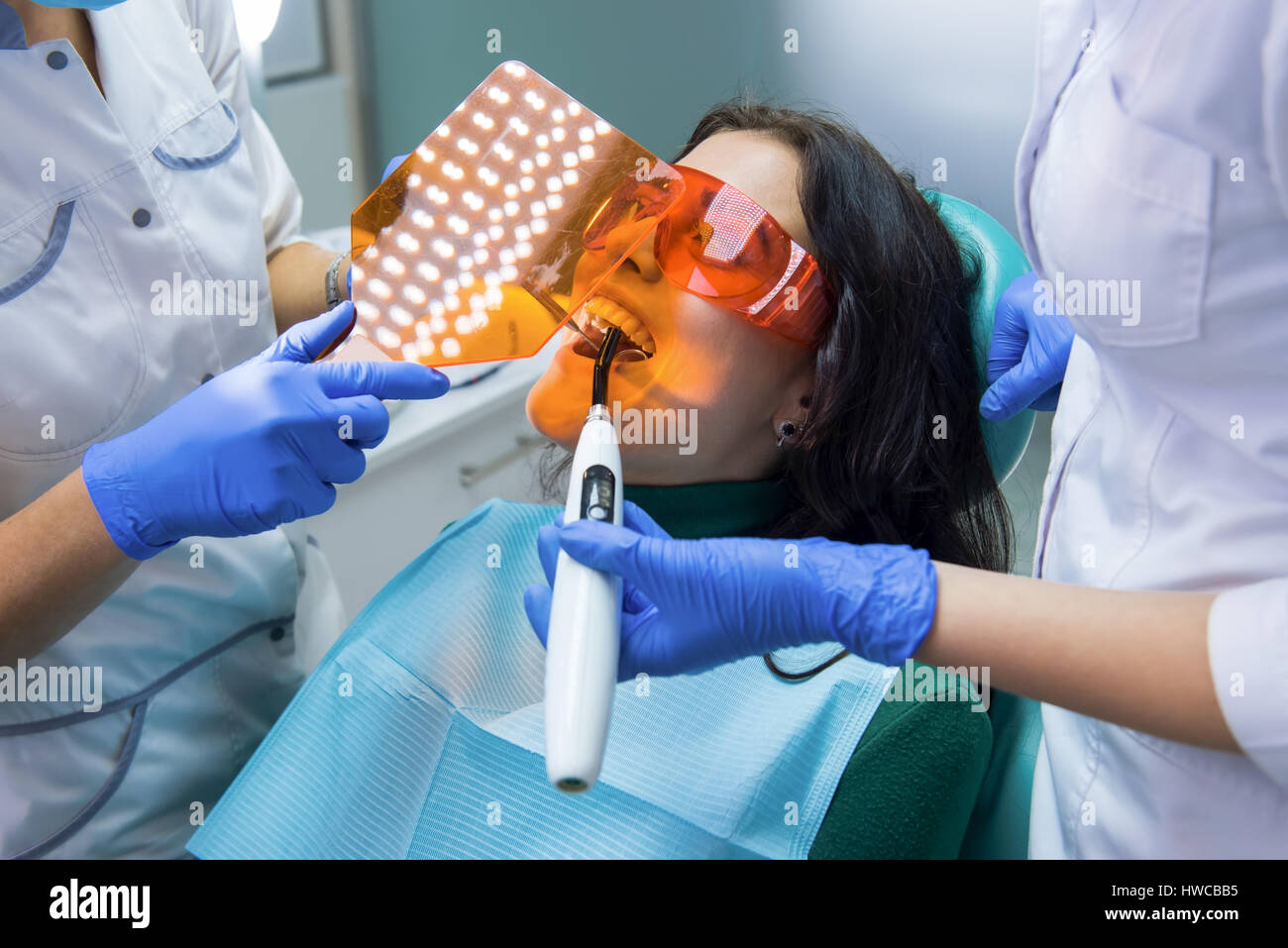 Dentist is using curing light Stock Photo - Alamy