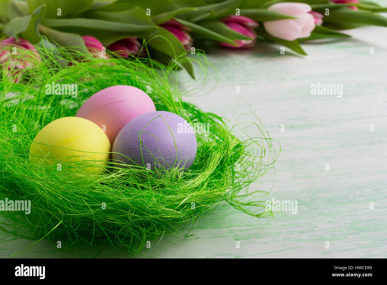 Three Easter eggs in green nest. Happy Easter greeting card or ...
