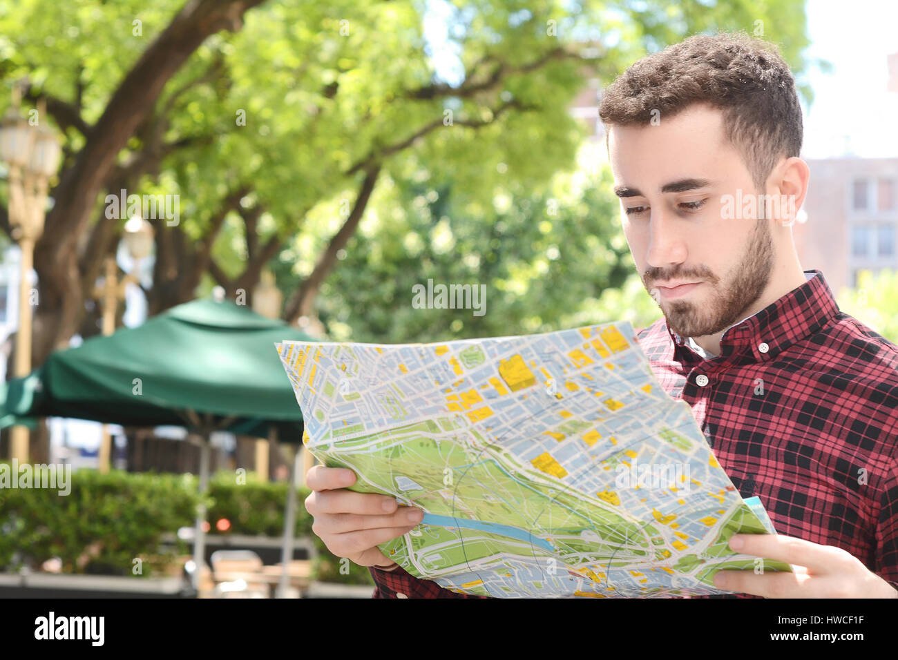 Portrait of a young handsome tourist man looking at a map. Tourism ...