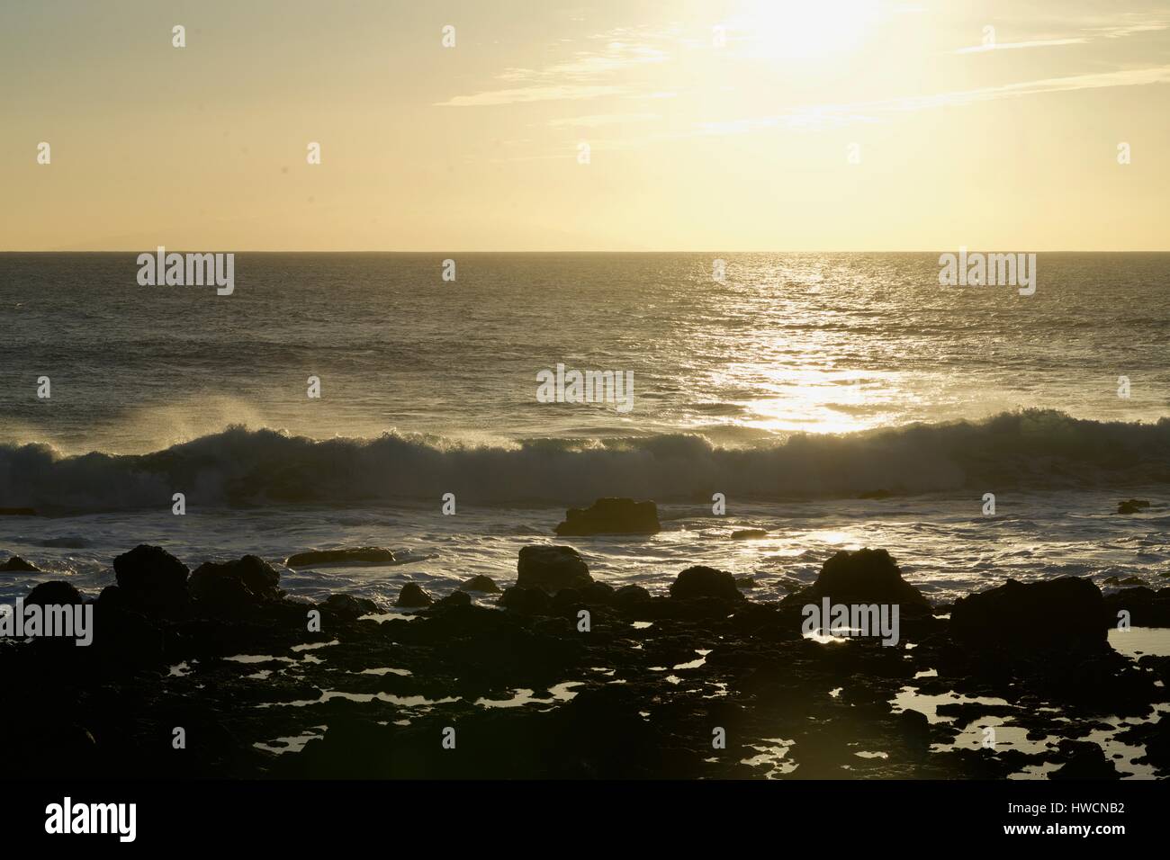 ocean waves with rocks under the sunset Stock Photo - Alamy